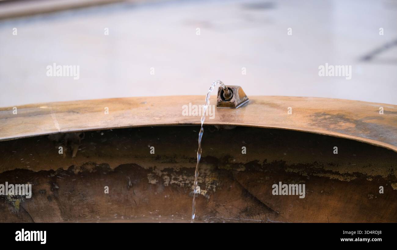 A serene close-up shot of a small stream of water falling from an aged ...