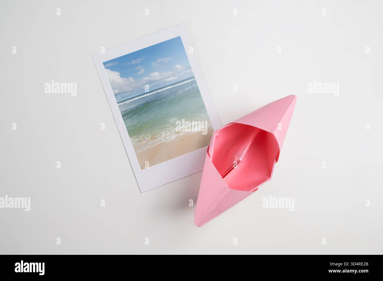 Instant print of beach landscape with pink paper boat on white ...