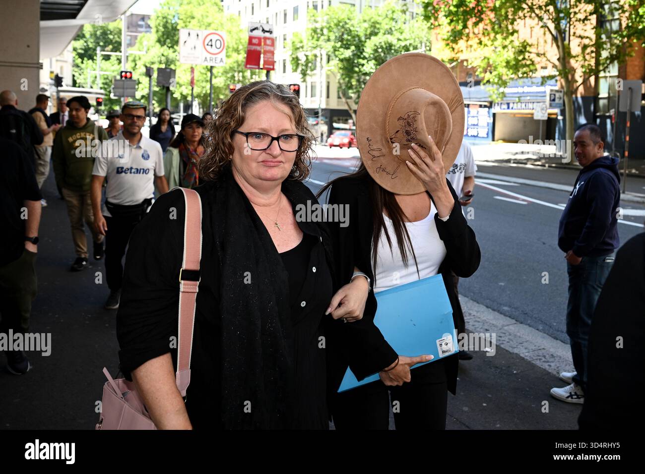 Nikolina Trajkovska (right) covers her face with a hat as she leaves ...