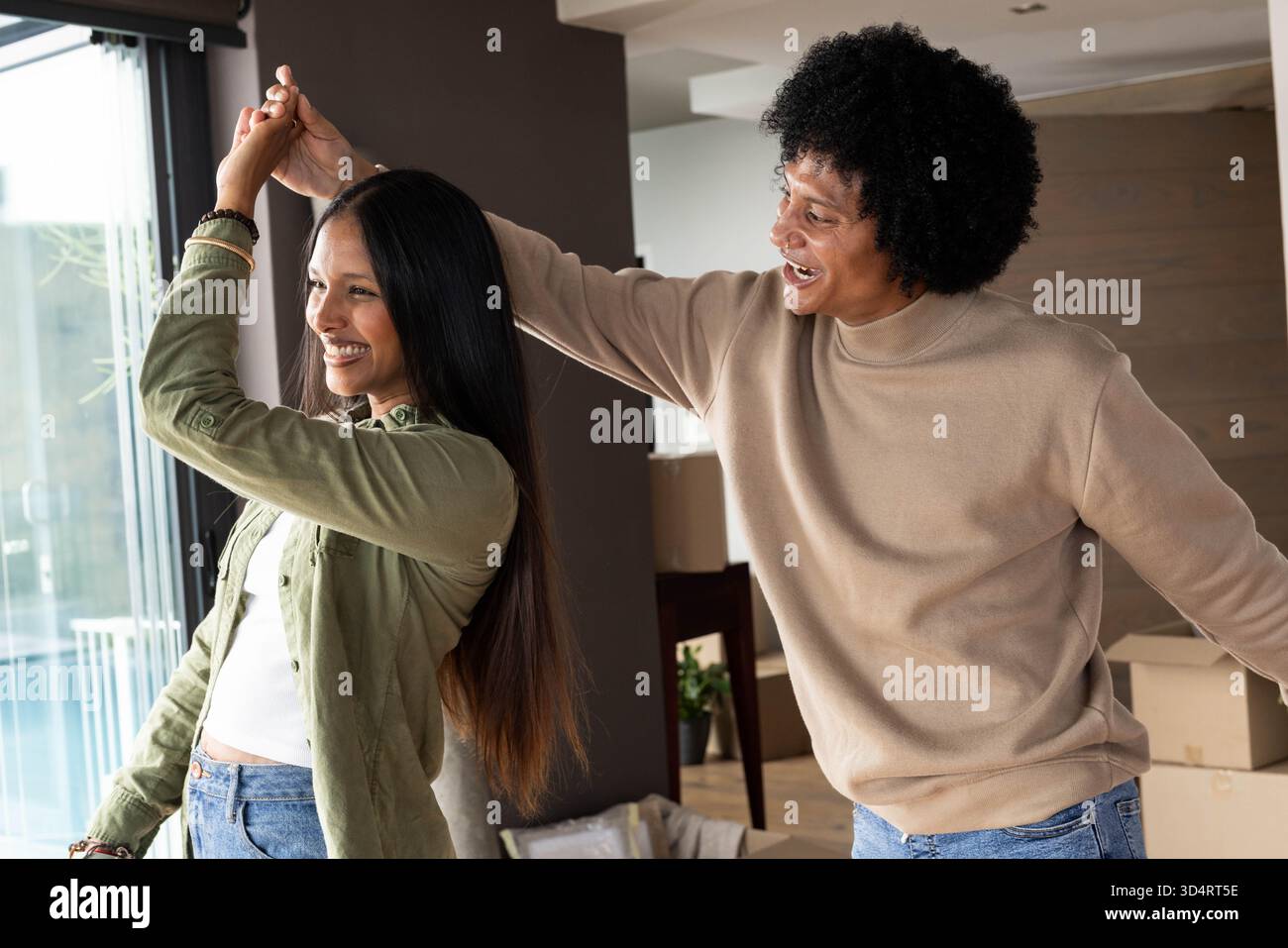 Twisting Diverse couple dancing in modern living room, with moving ...
