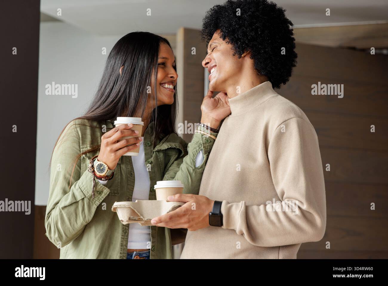 Touching partner's face, diverse couple holding coffee cups at modern ...