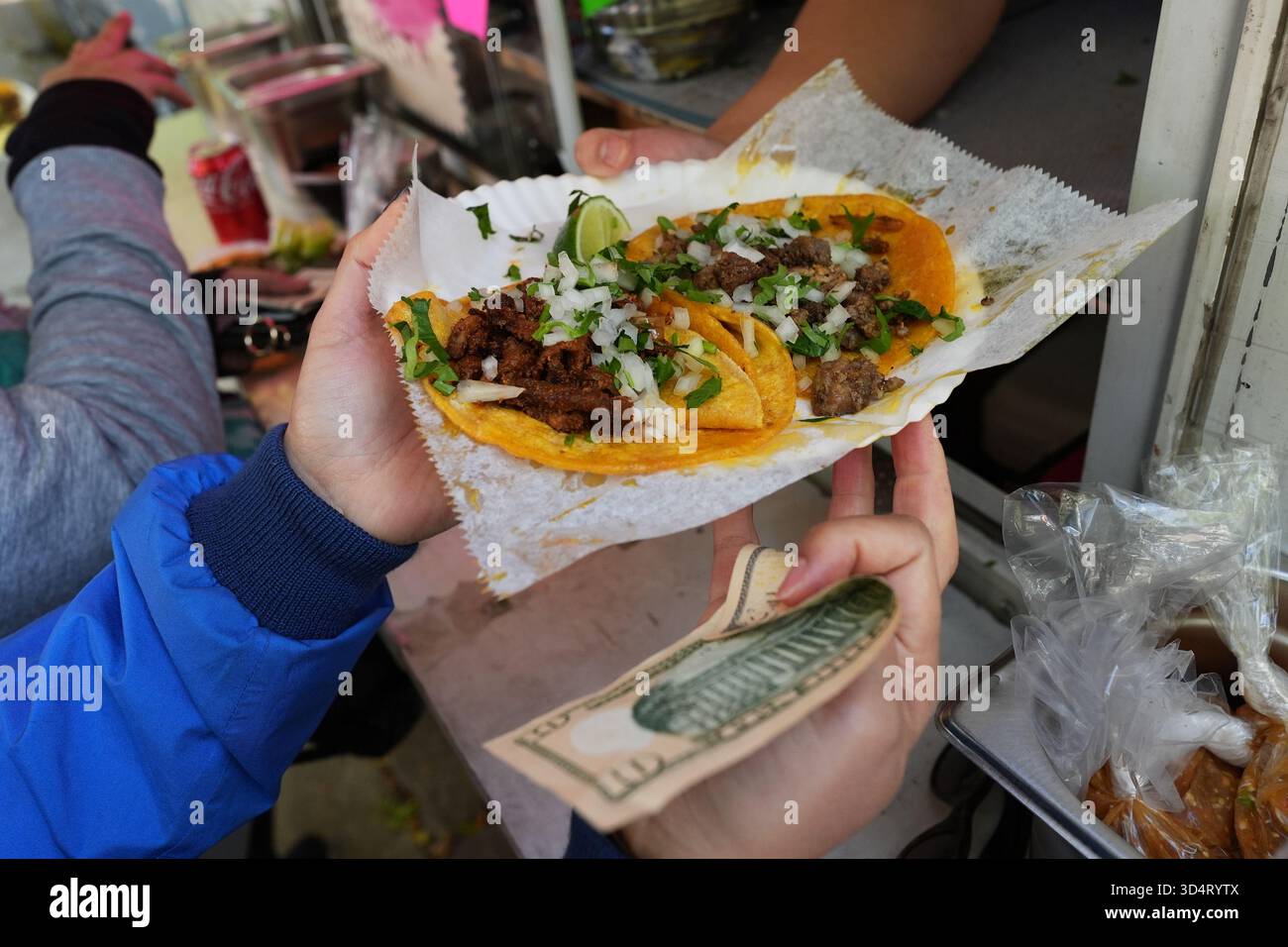 A bicyclist receives food from a street vendor Yulisa Robles, right, at ...