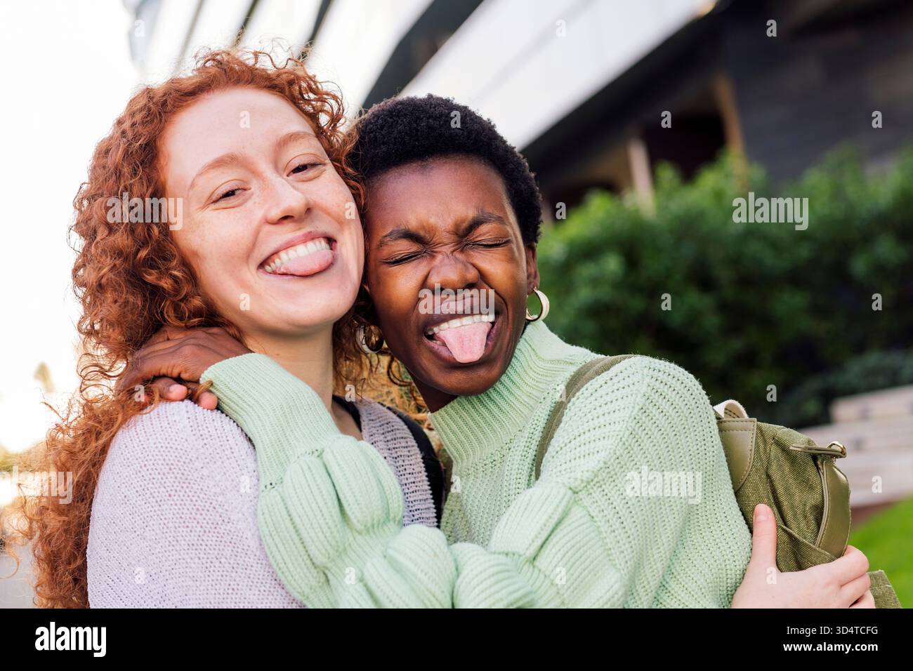 two young women hugging and sticking out tongue Stock Photo - Alamy