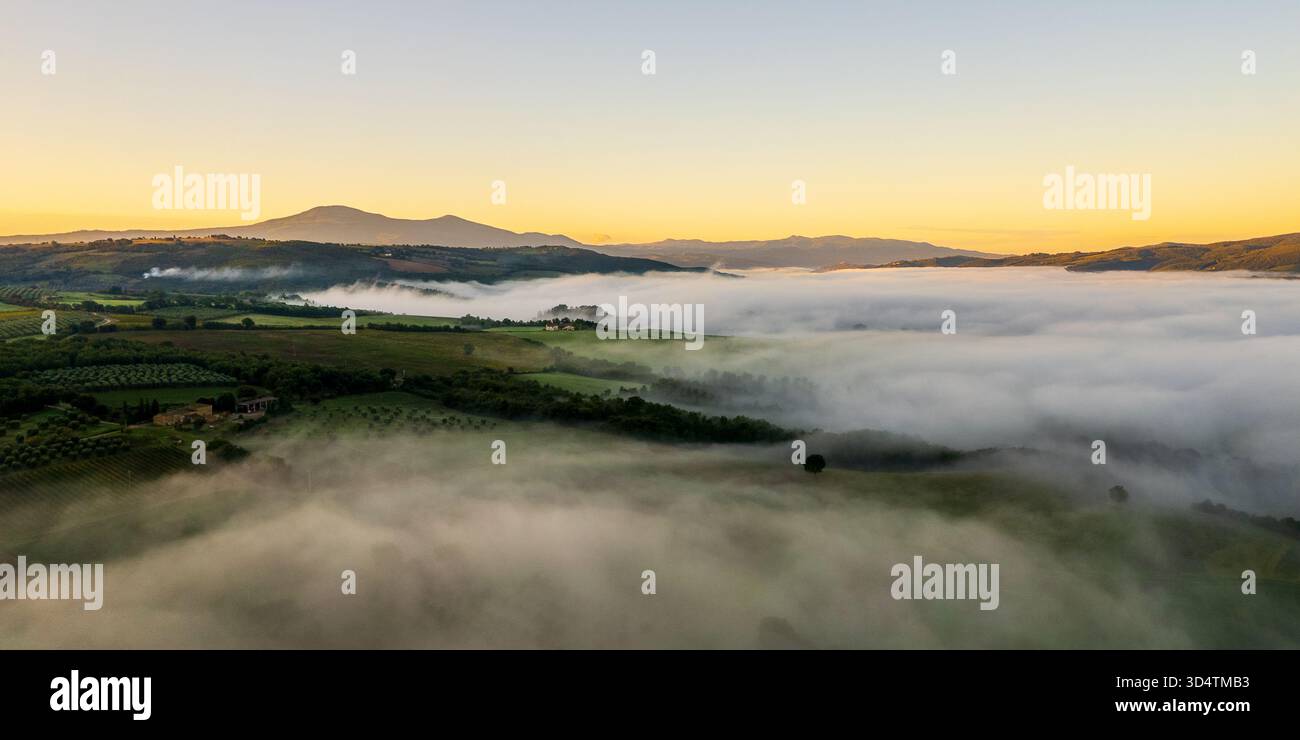 Aerial view of a tranquil morning unveils a sea of fog blanketing the ...