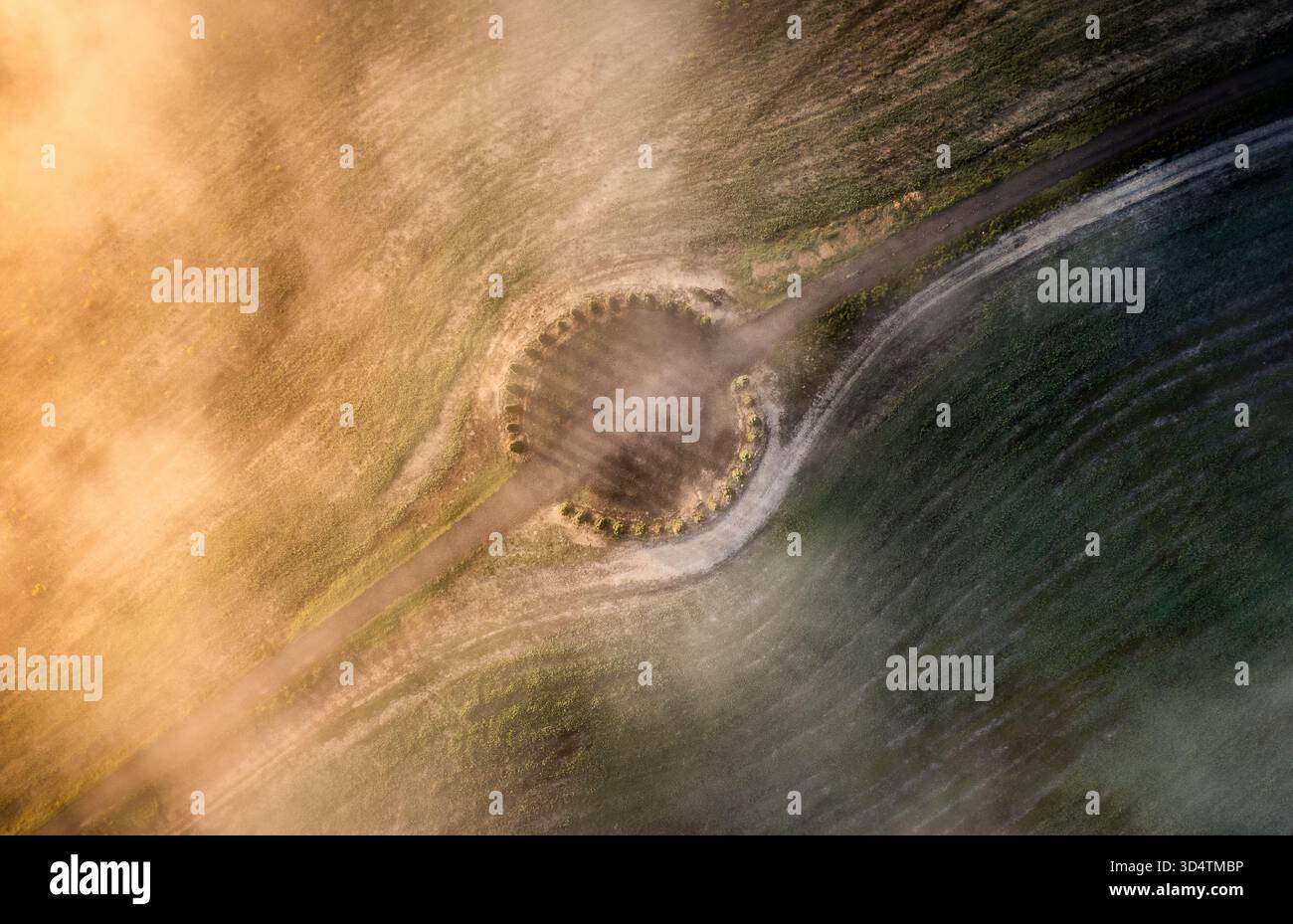 Aerial view of a roundabout cloaked in mist, bisecting fields in the ...