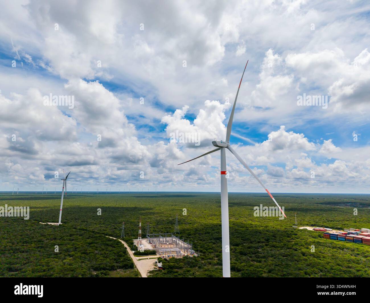 An aerial view of a wind turbine shows its massive blades spinning ...