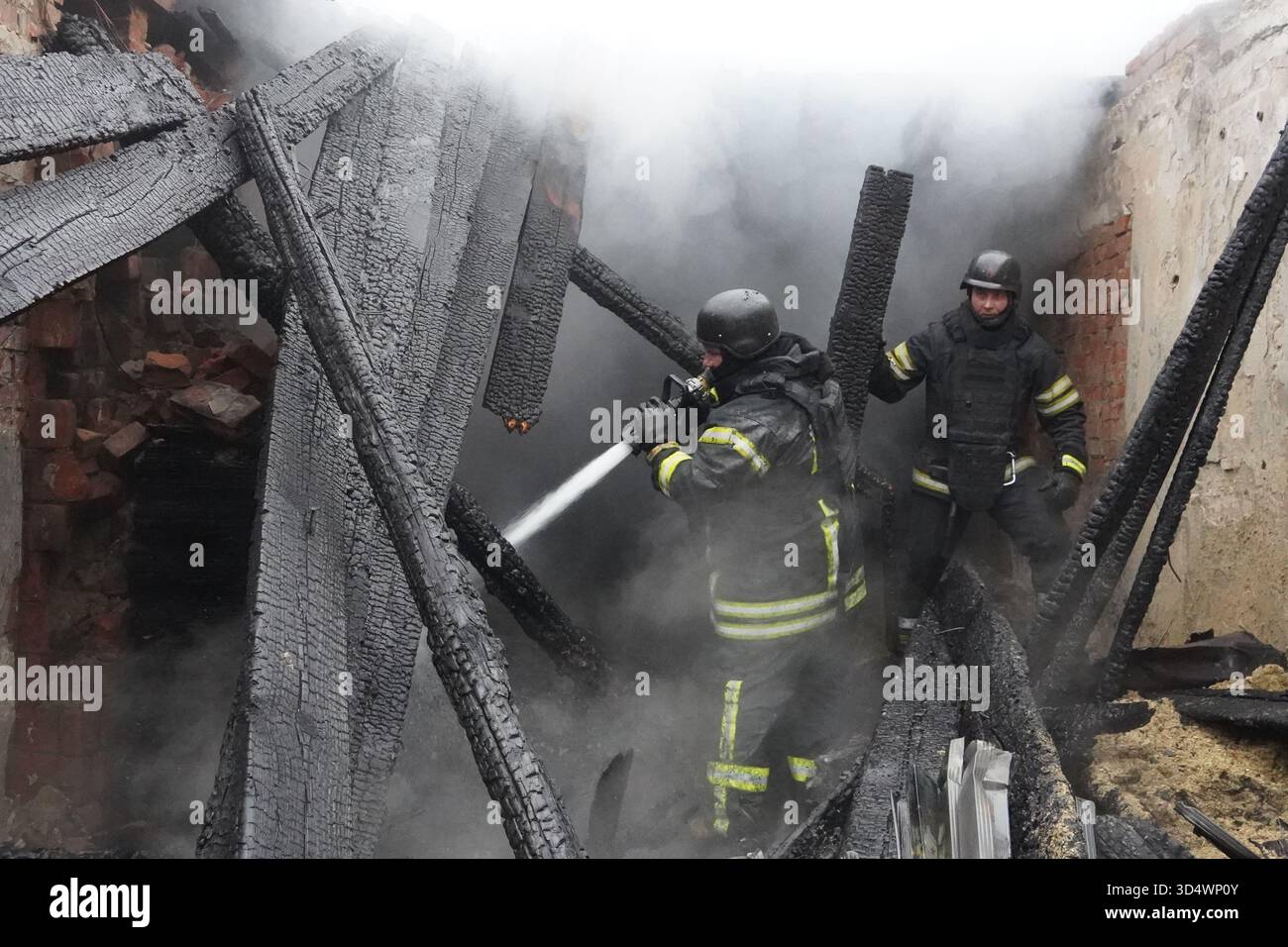 Rescue workers put out a fire of a building damaged by a Russian strike ...