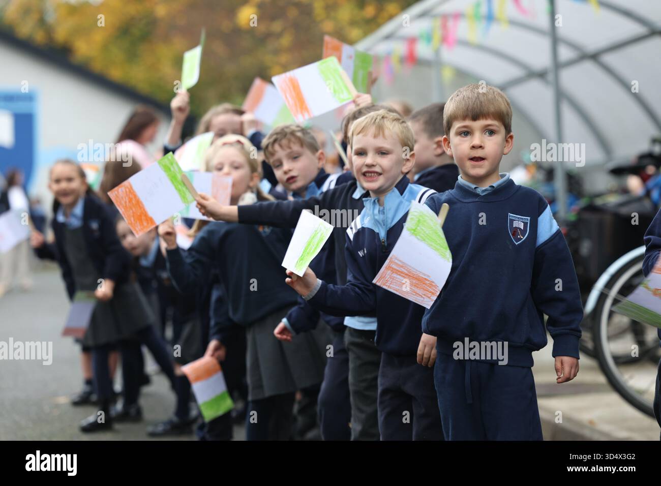 Pupils wave flags during President Catherine Connolly's visit to ...