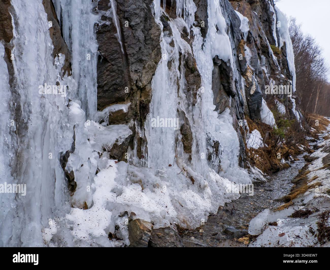 Ice overhangs along the road. Large icicles and lumps of frozen water ...