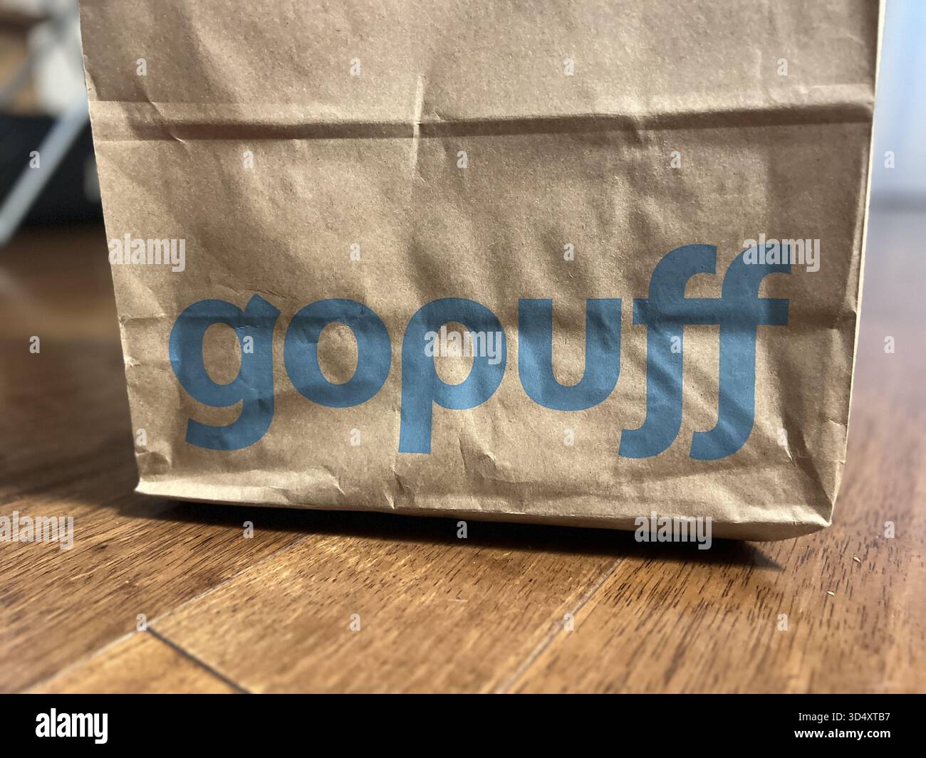 Close-up of a Gopuff-branded paper delivery bag on a hardwood floor ...
