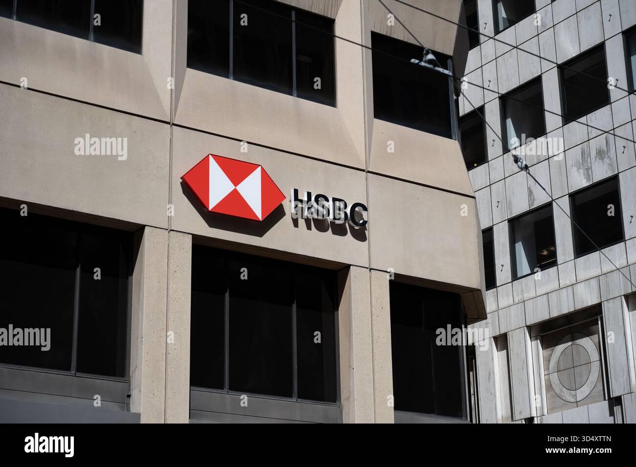 Facade of HSBC bank branch with red and white logo on concrete office ...