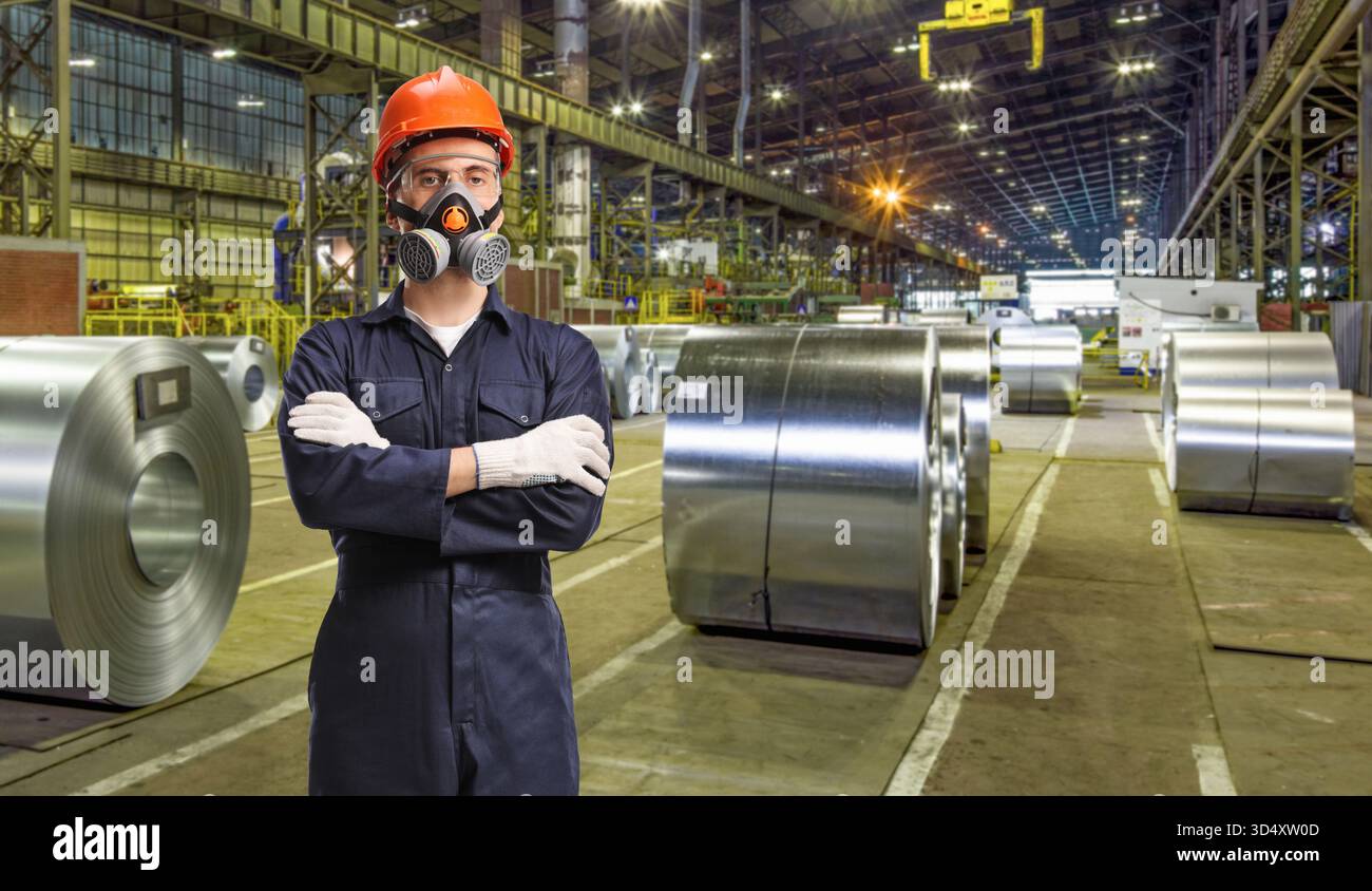 Factory worker wearing health and safety equipment inside a steel mill ...