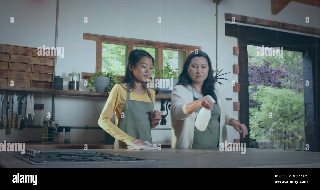Cleaning two women wearing aprons wiping counter in rustic kitchen ...