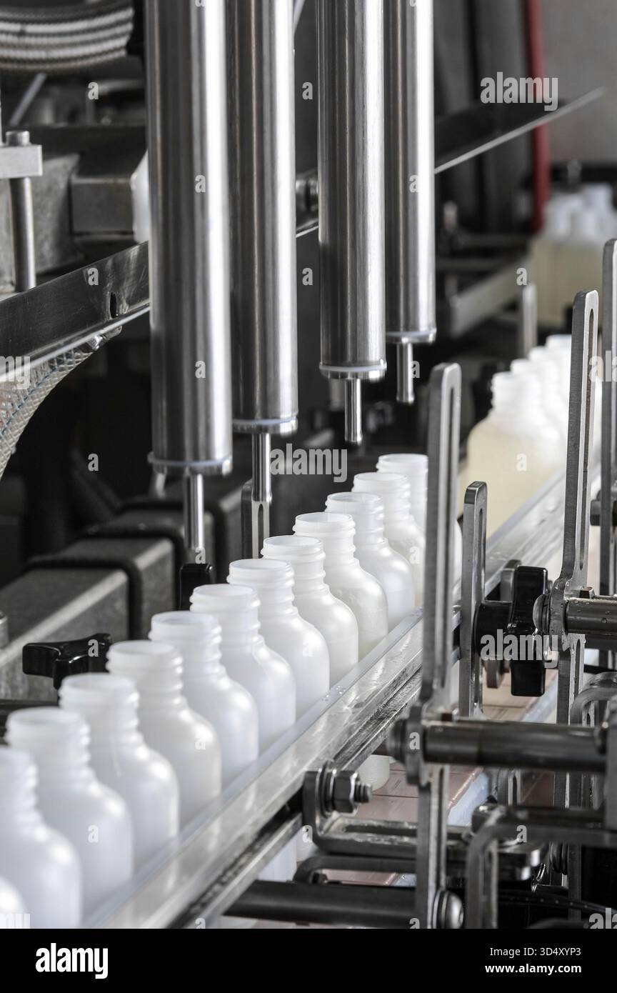 Bottles being filled at filling station on automated processing ...