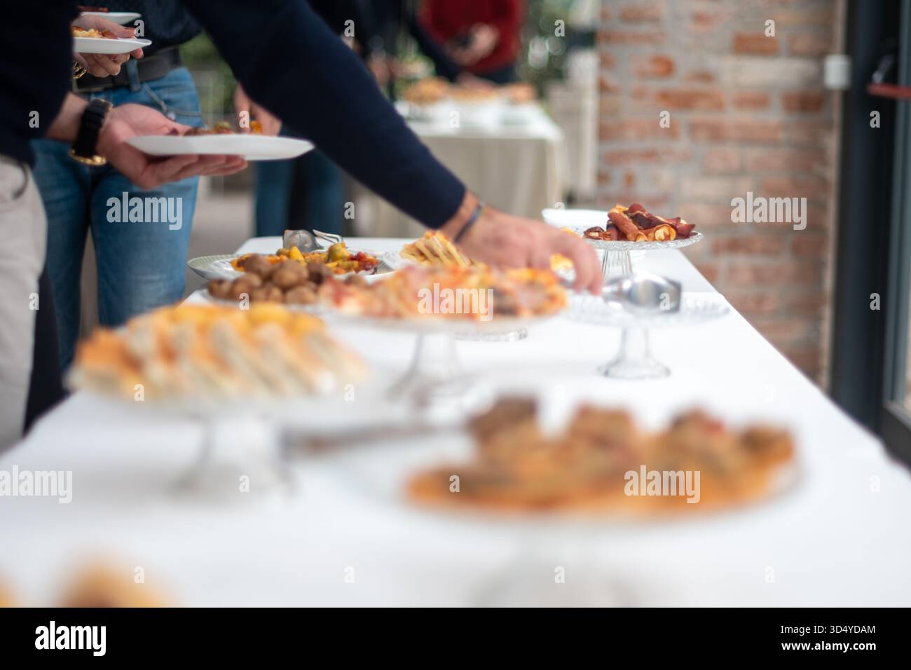 People grabbing food from a buffet table at a social gathering event ...
