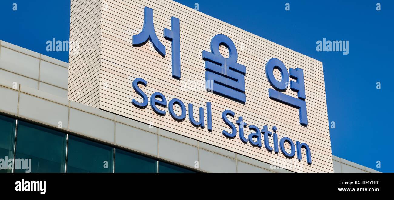 Seoul Station sign standing against a clear blue sky, translating to ...