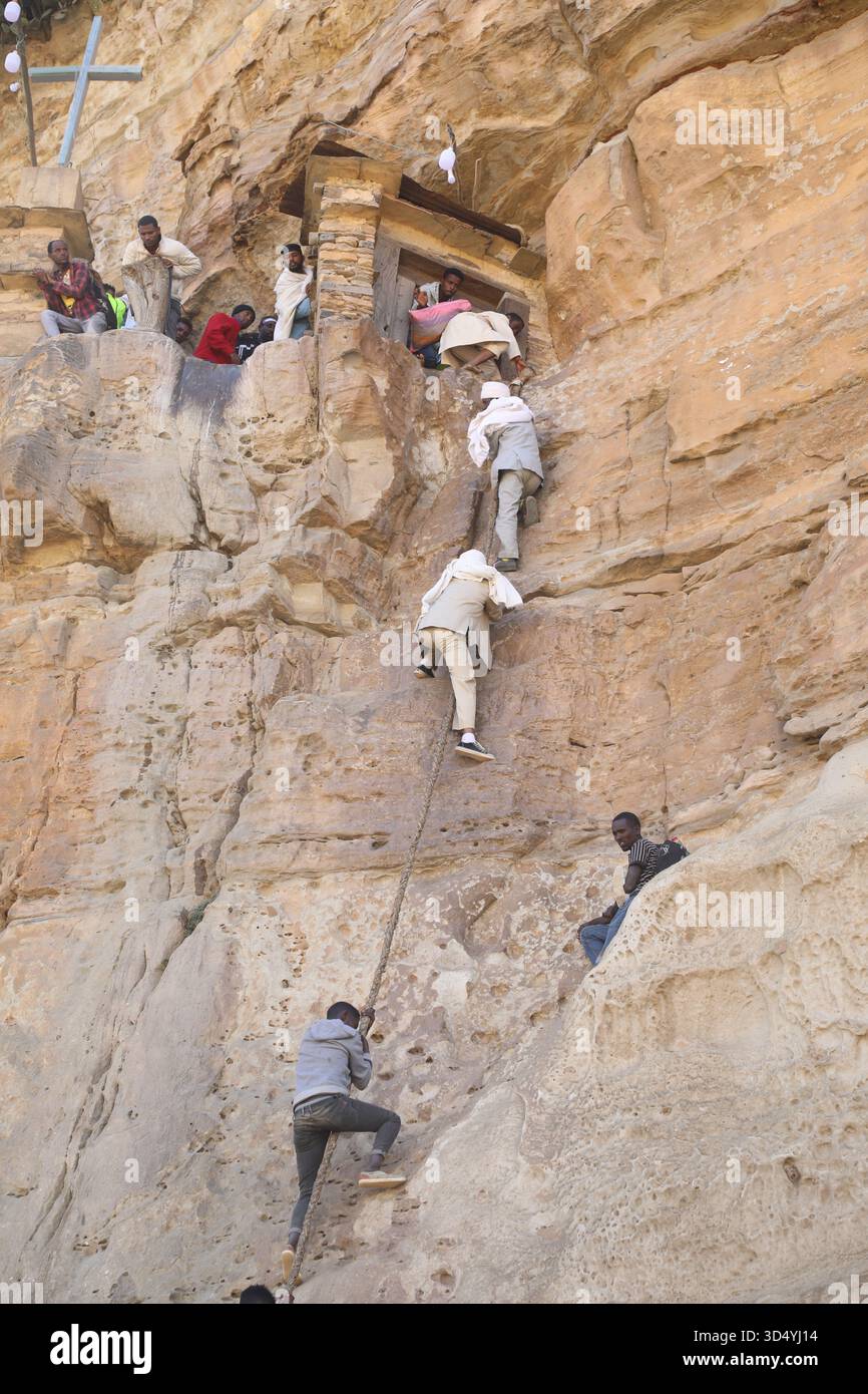 Pilgrims and visitors ascend the sheer cliff face using a thick leather ...
