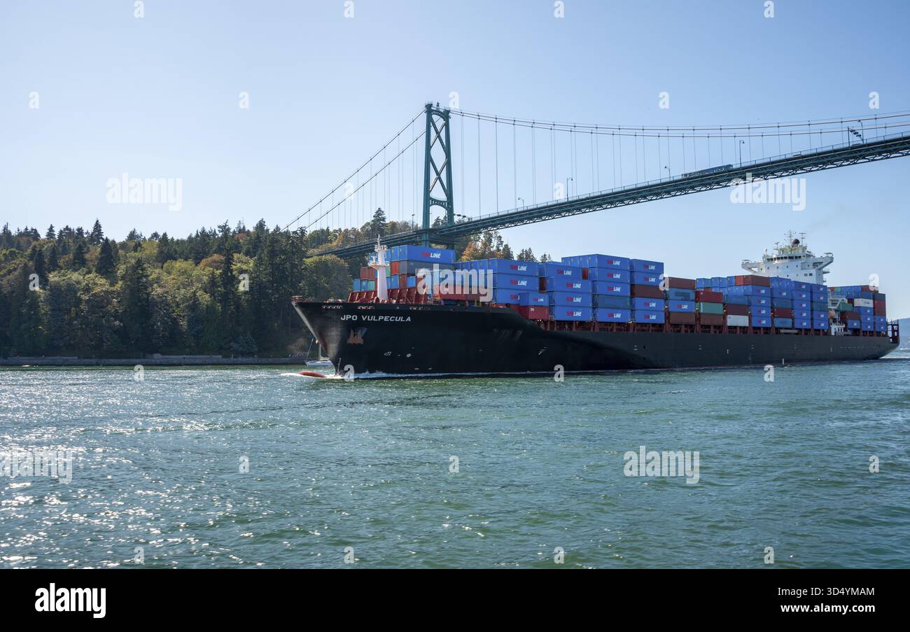 Container ship loaded with containers sails under the Lions Gate Bridge ...