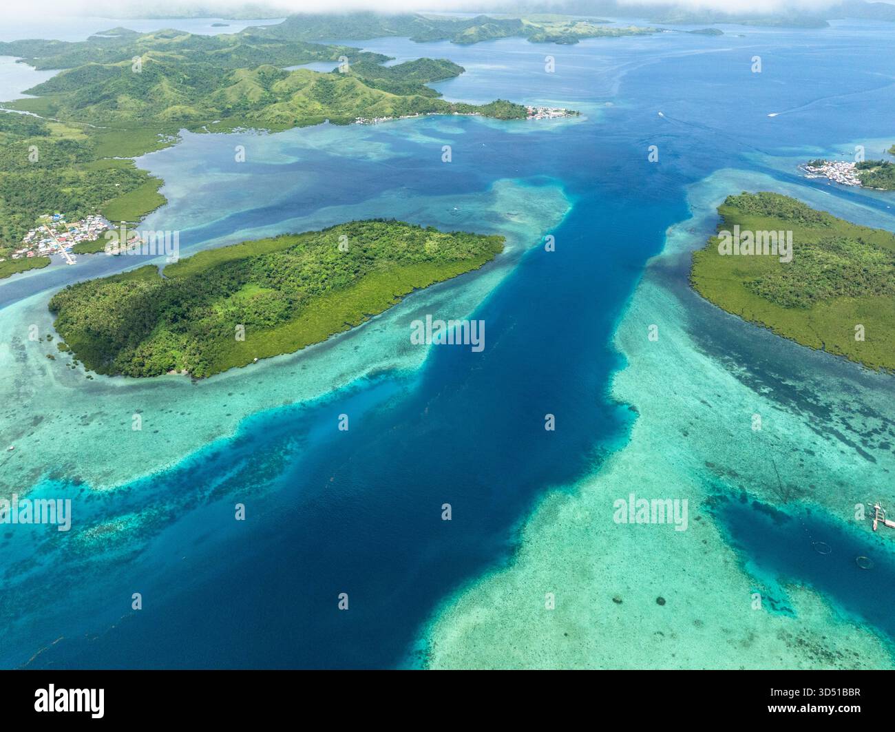 Turquoise water channel running between forested green islands with ...