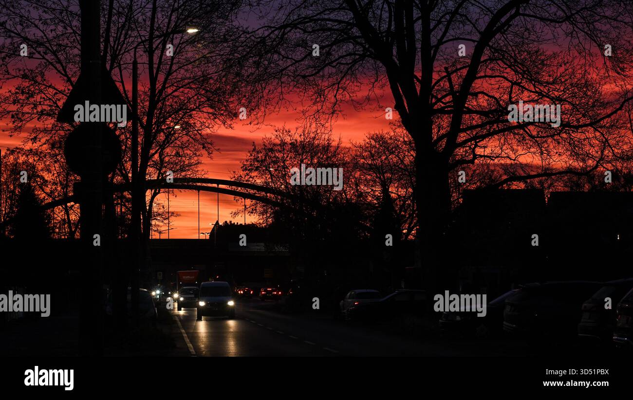 13 November 2025, Berlin: Red colored sky over a street during morning ...