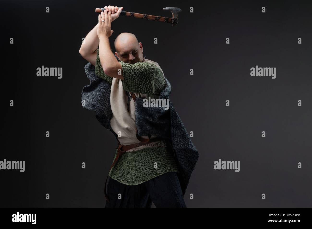 Medieval Viking warrior portrayal: bald man with weapons and fur on ...