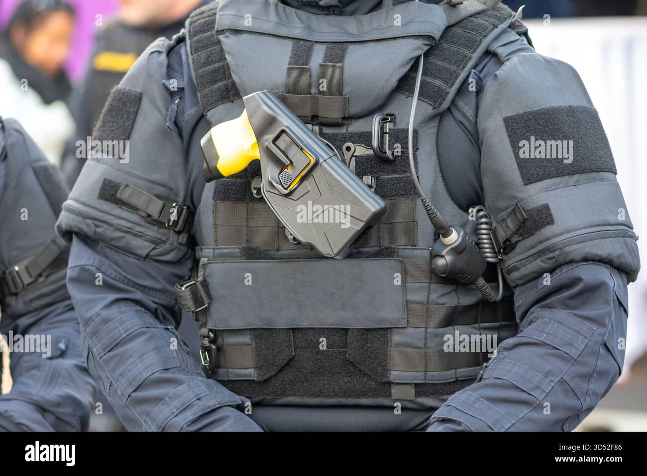 A fighter is standing outside in a bulletproof vest with a taser ...