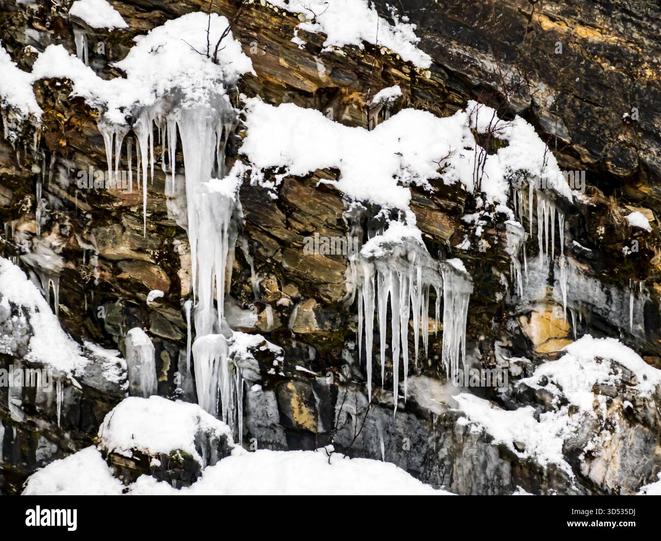 Ice overhangs along the road. Large icicles and lumps of frozen water ...