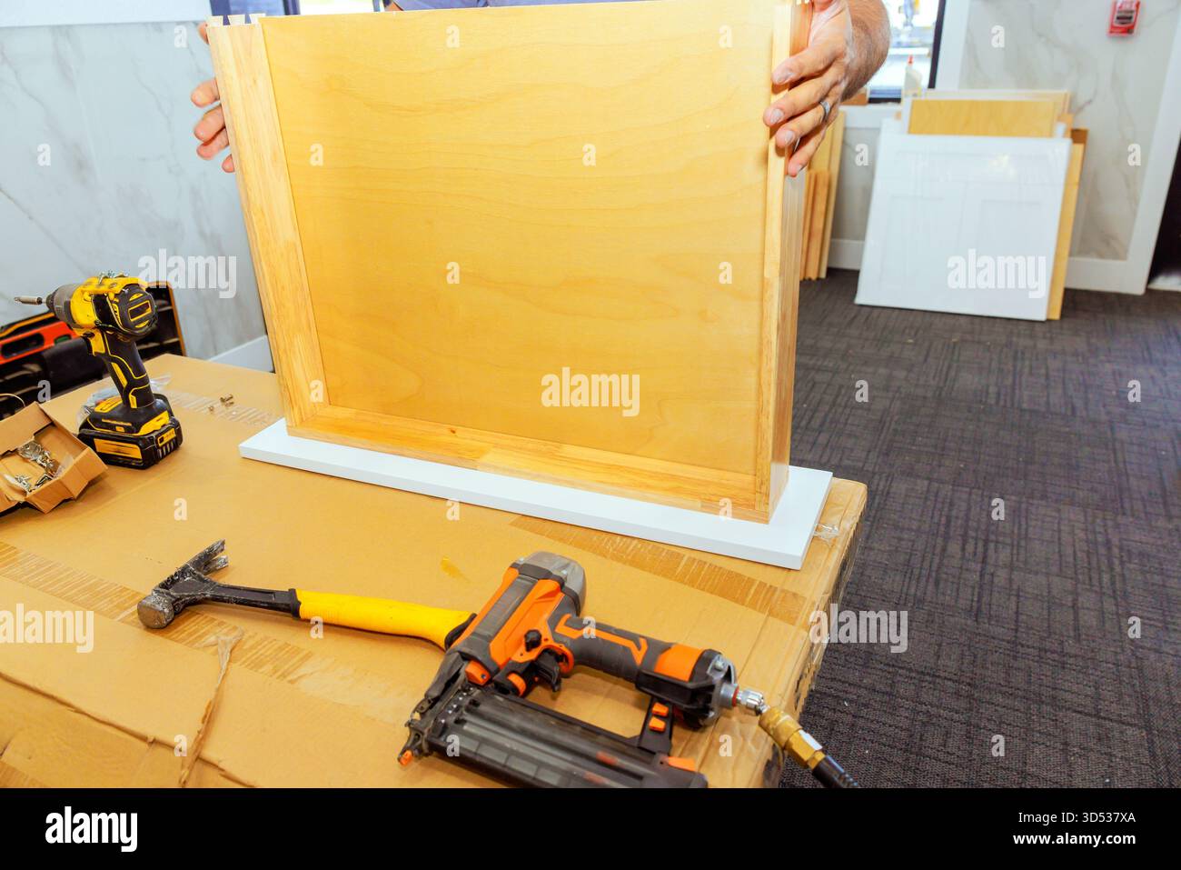 Wood worker is working on assembling wooden drawer frame while using ...