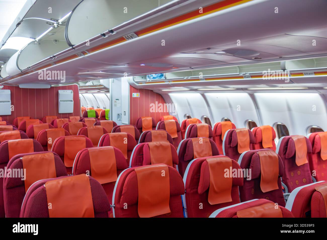 Interior of a passenger plane with empty red seats with orange ...