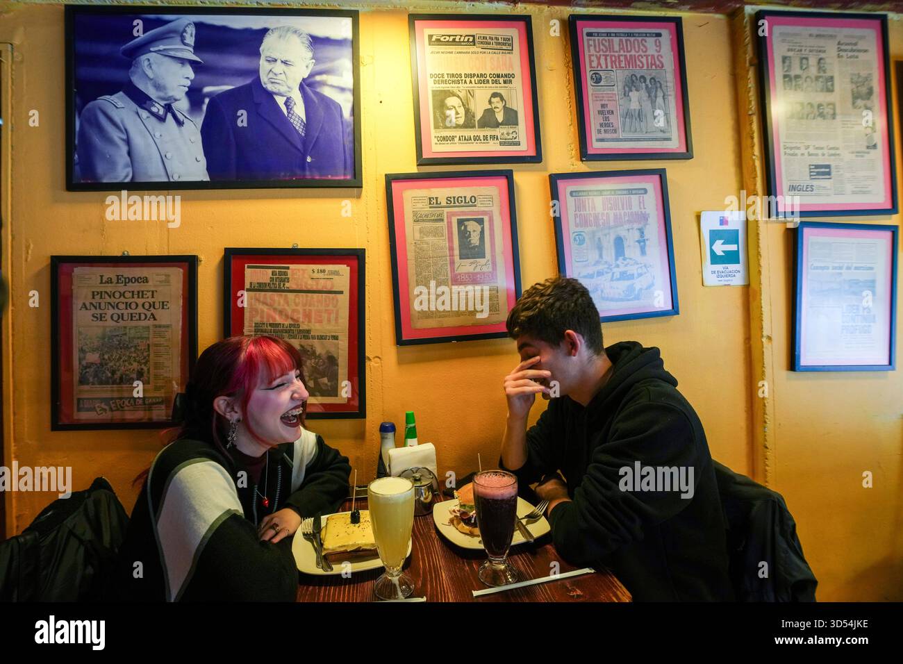 A couple sit in the Cafe Cronica where a photo of dictator Augusto ...