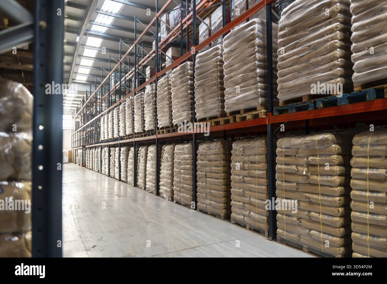 Spacious industrial warehouse aisle with pallets of identical sacks ...