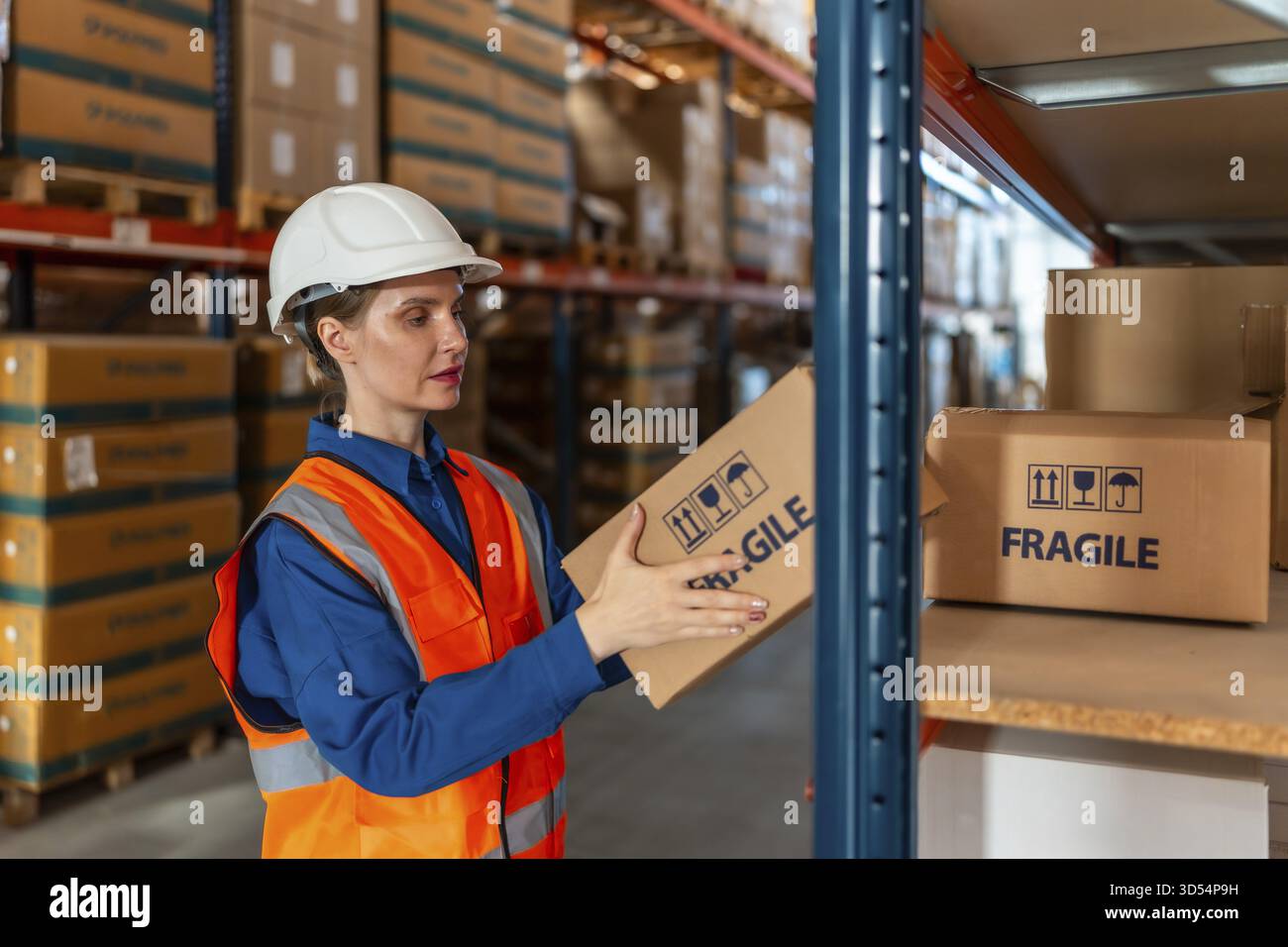 Worker in safety gear handling a fragile package, organizing inventory ...