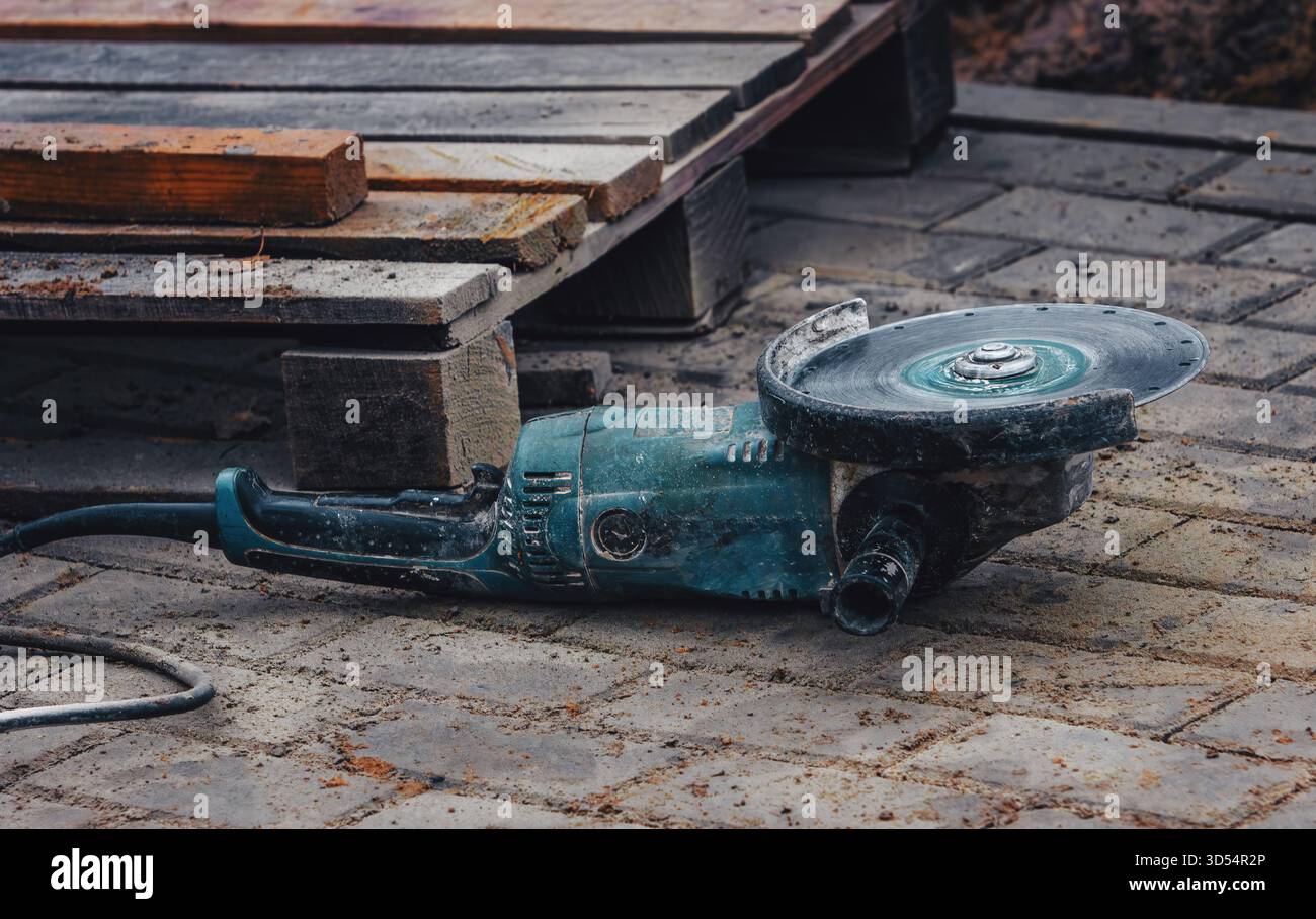 An industrial angle grinder lying on the ground among wooden pallets ...