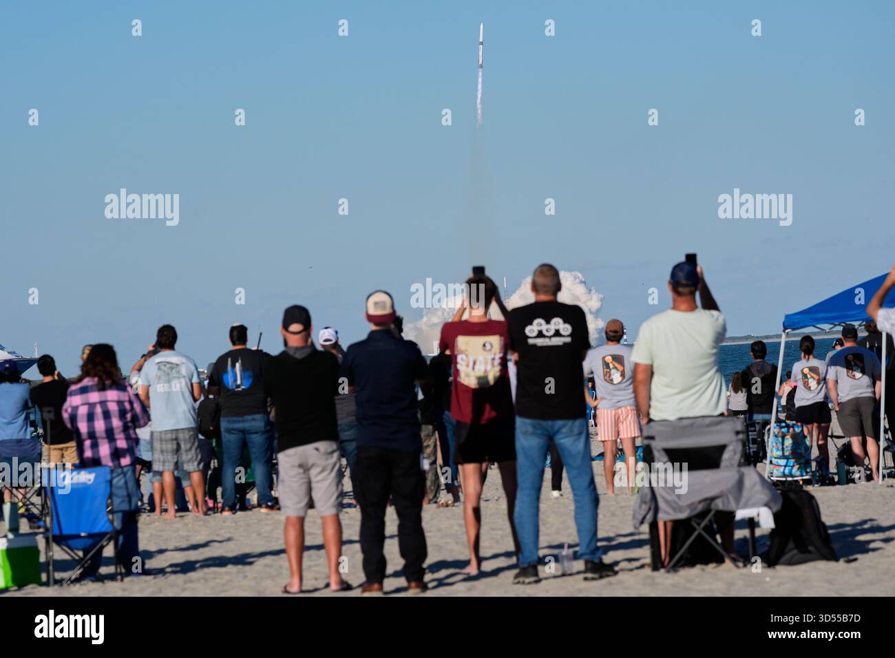 Spectators on the beach watch a Blue Origin New Glenn rocket as it ...