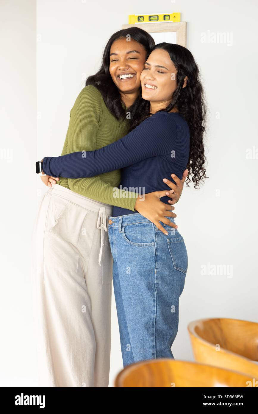Hugging diverse female friends smiling in minimalistic home interior ...