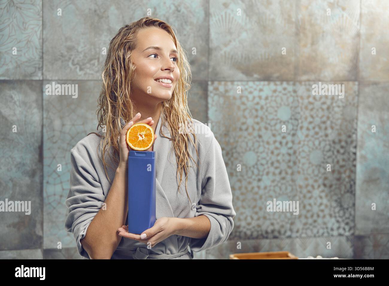Shampoo with orange extract. Woman holding packaging of shampoo with ...