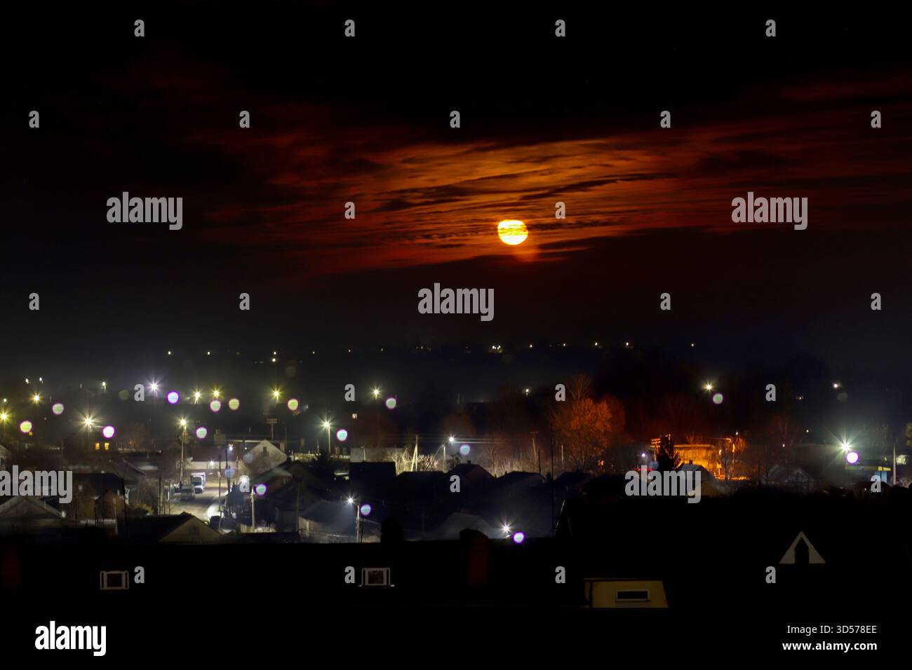 Full moon behind orange clouds over suburban neighborhood with ...
