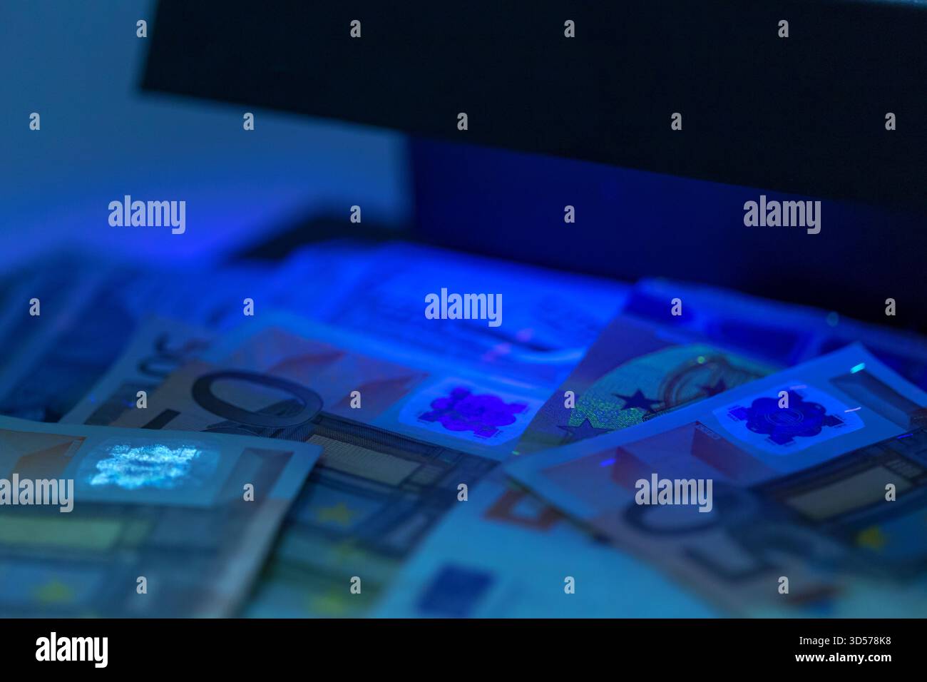 Currency in a dark box under ultraviolet light reveals security ...
