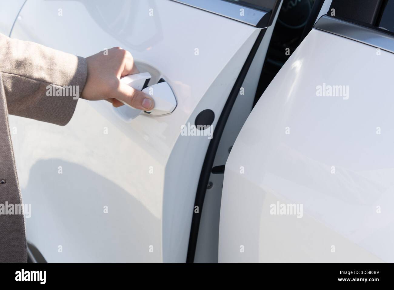 Man's hand is pulling the exterior car door handle to open the white ...