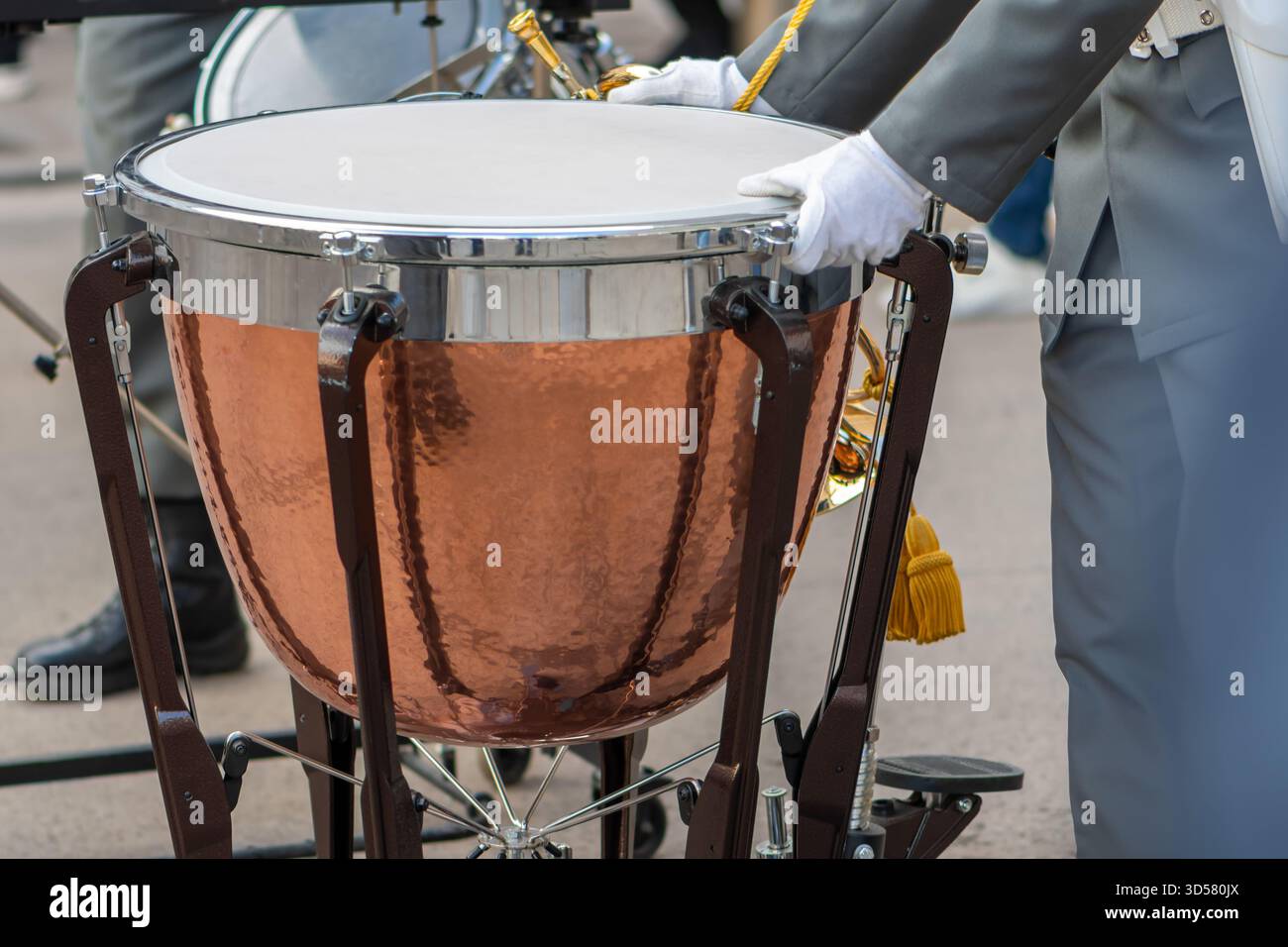 A large timpani with a shiny copper surface is placed in front of the ...