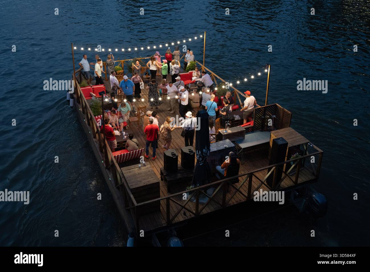 Tourists dance and drink on a floating raft type boat on the Kura River ...