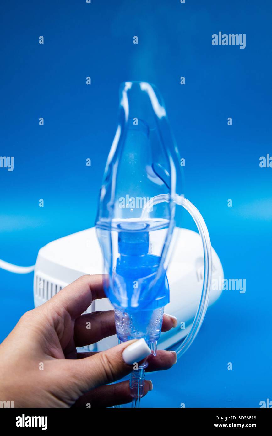 Close-up side view of a blue inhalation mask from which vapors are ...