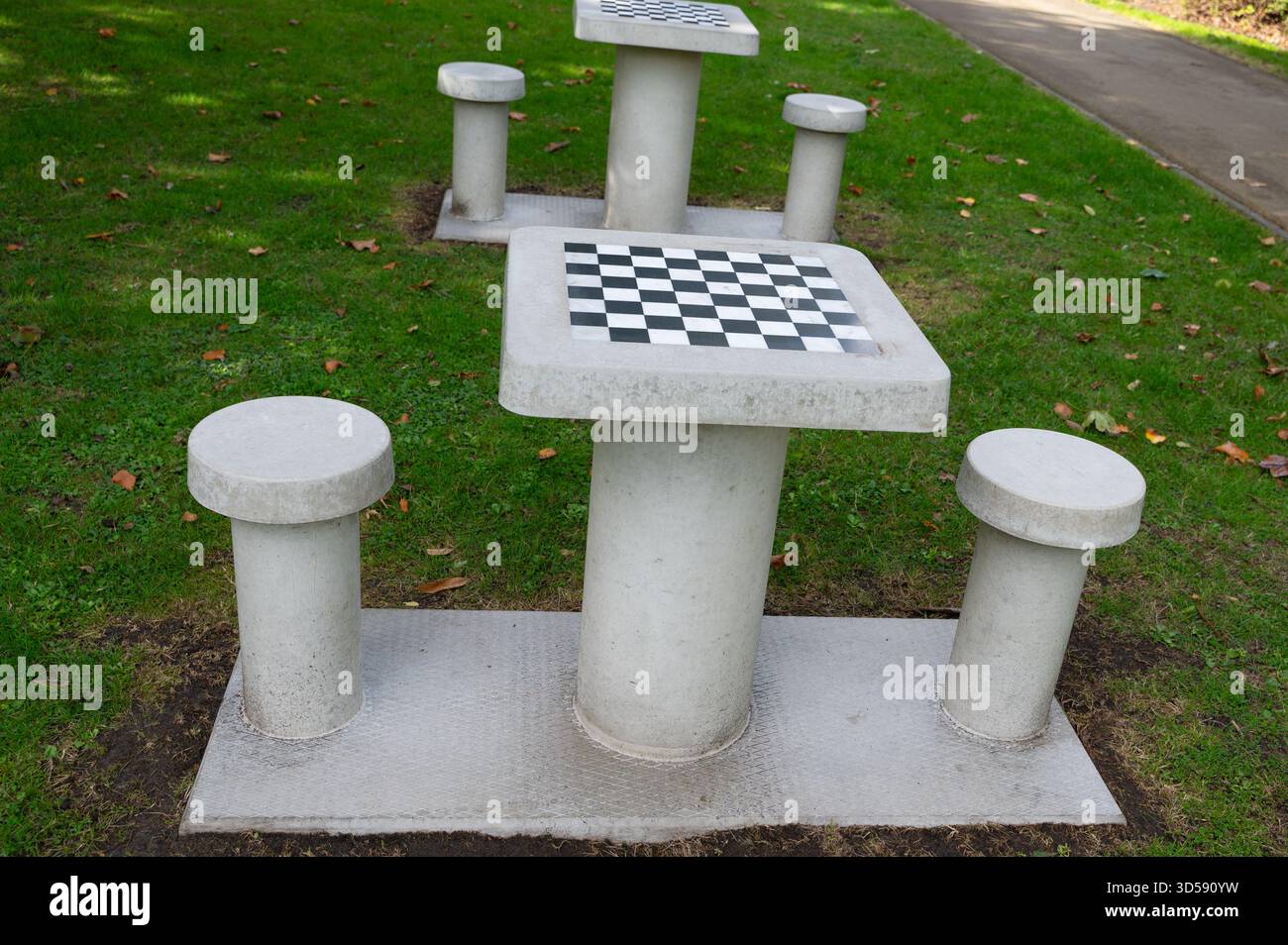 concrete chess table with stools, park setting beside paved path and ...