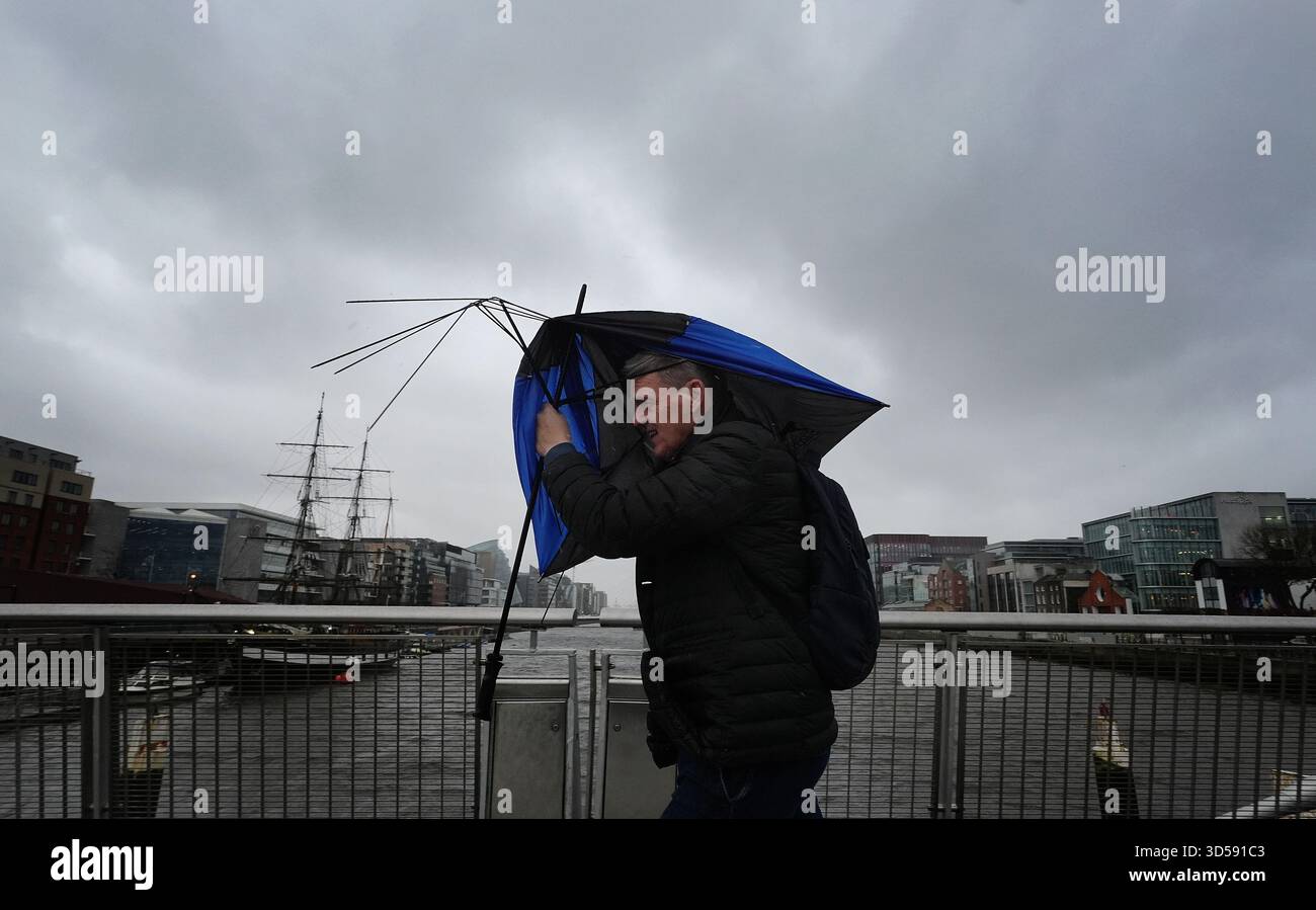 A person holding an umbrella crosses the Sean O'Casey bridge a wet and ...
