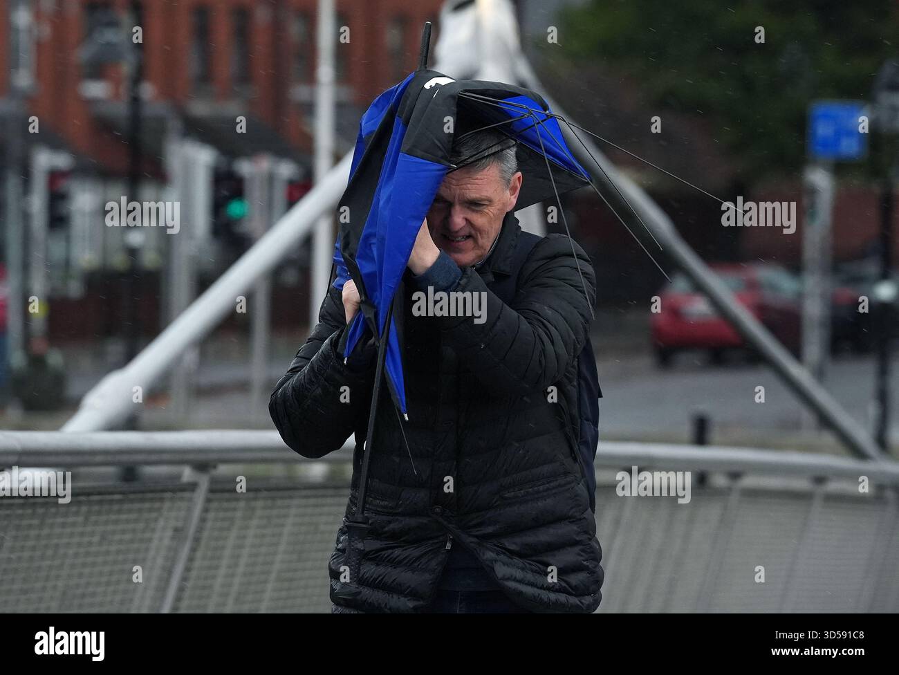 A person holding an umbrella crosses the Sean O'Casey bridge a wet and ...