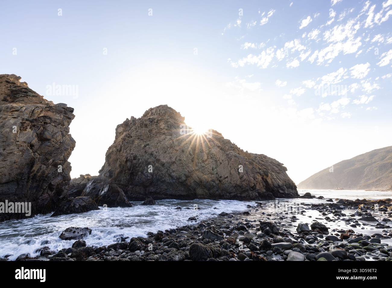 Sunburst behind rugged coastal rock walls above the surf at Pfeiffer ...
