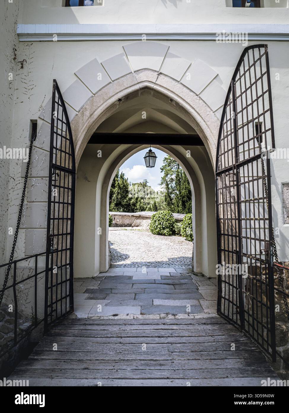 A medieval-style arched gate stands open, leading into a cobblestone ...
