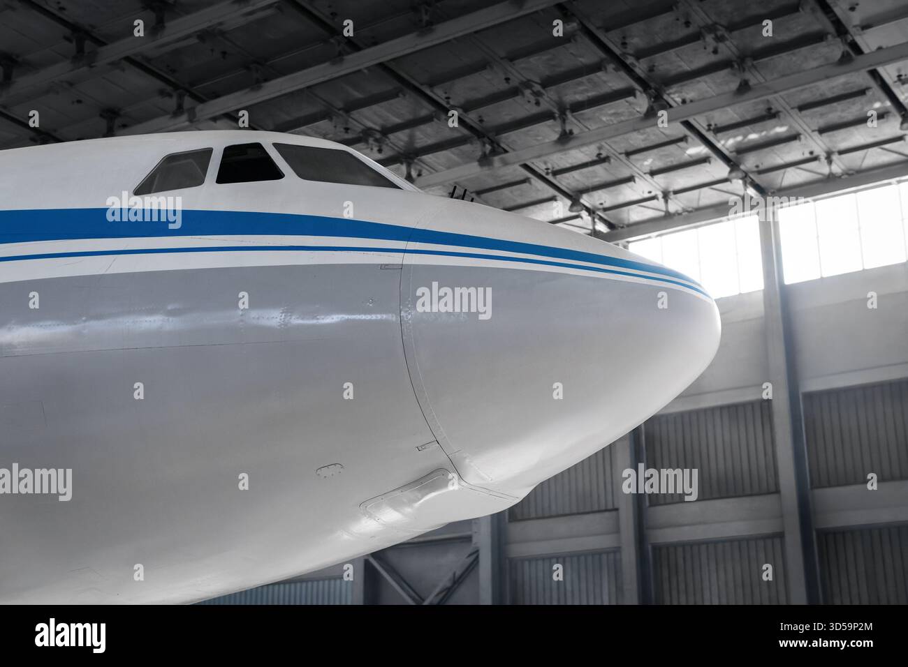 Front part of passenger aircraft in a hangar. Close-up view of white ...
