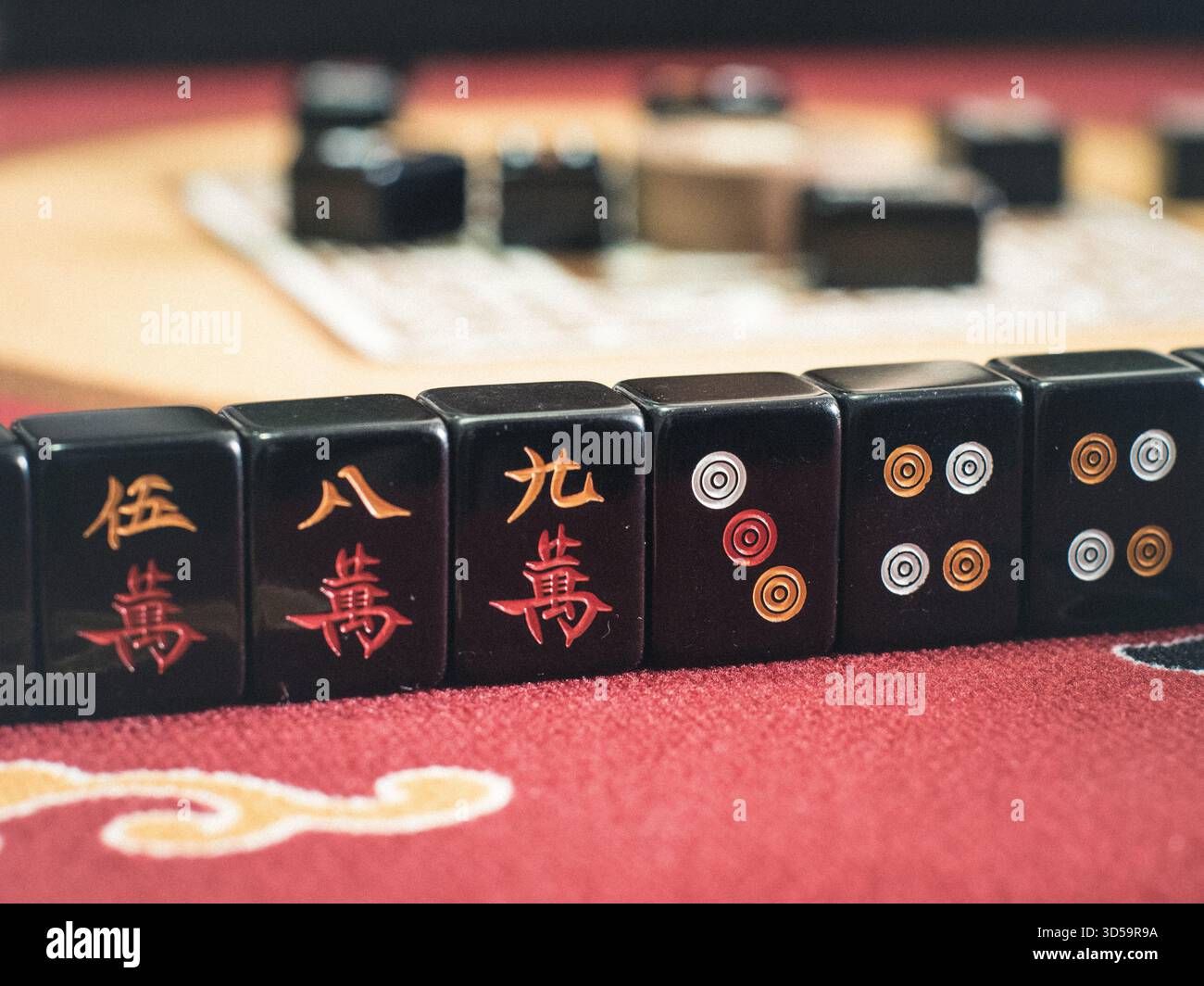 A detailed macro view of black Mahjong tiles arranged in a row on a red ...