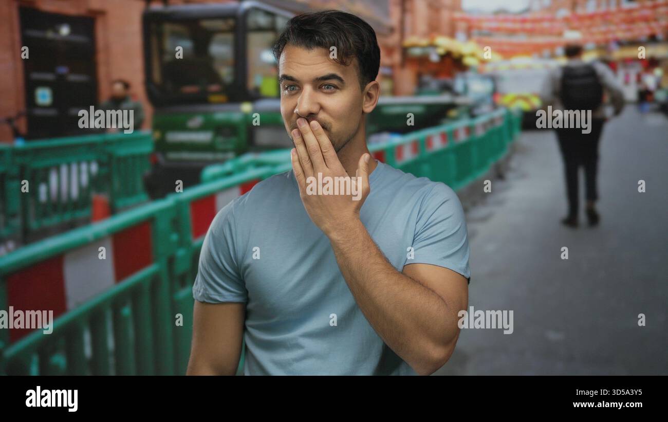 Young man surprised at construction site outdoors with hand over mouth ...